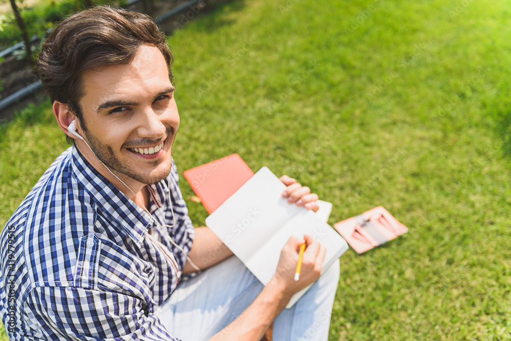 Carefree guy doing homework in park Stock Photo | Adobe Stock