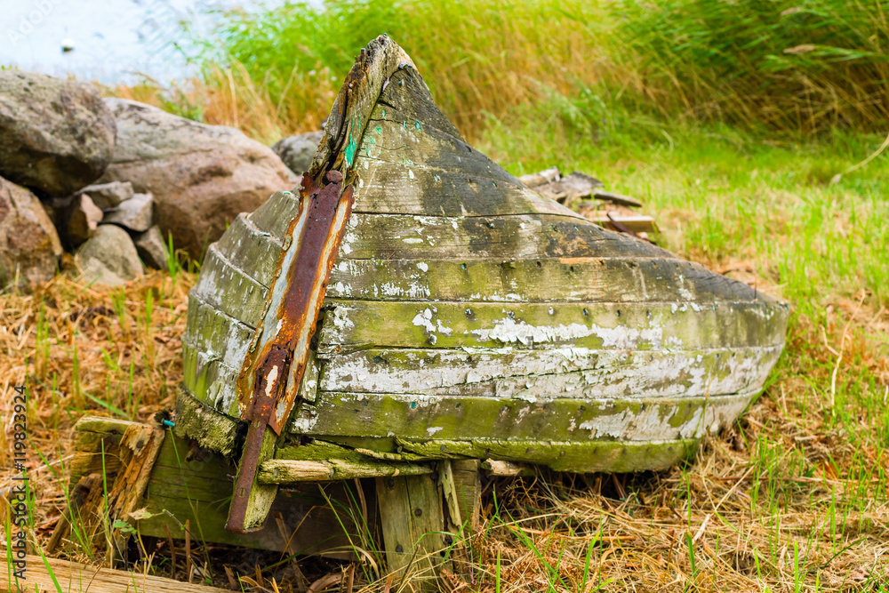 Very old rotting boat lying on dry land wasting away. Nature is slowly ...
