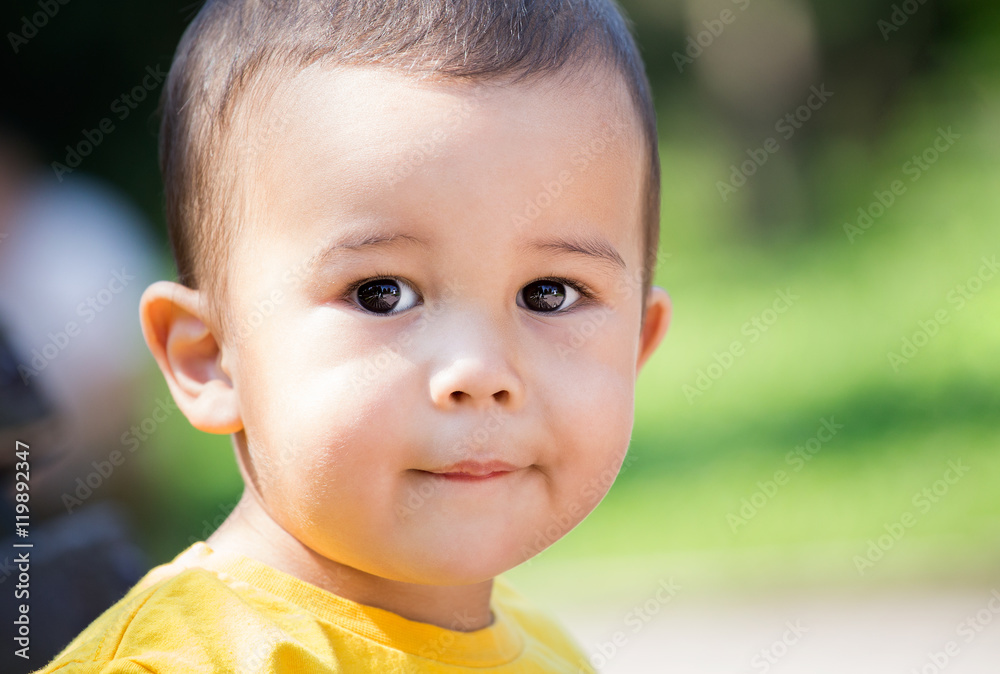 Portrait of a little boy with eyes wide open. The child smiles pursing ...