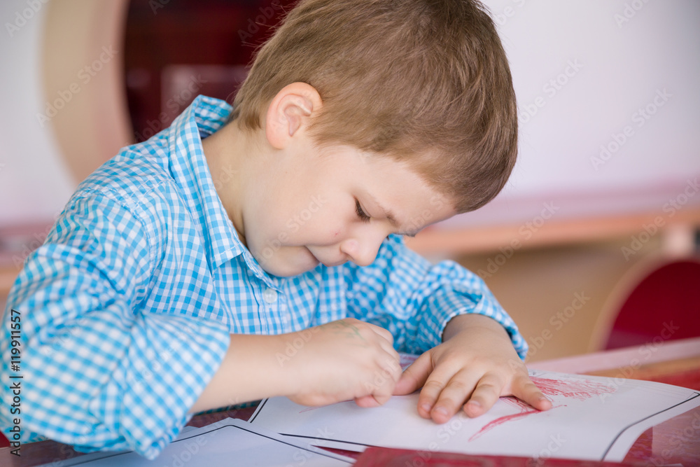 Cute little preschool kid boy in a blue plaid shirt drawing on the ...