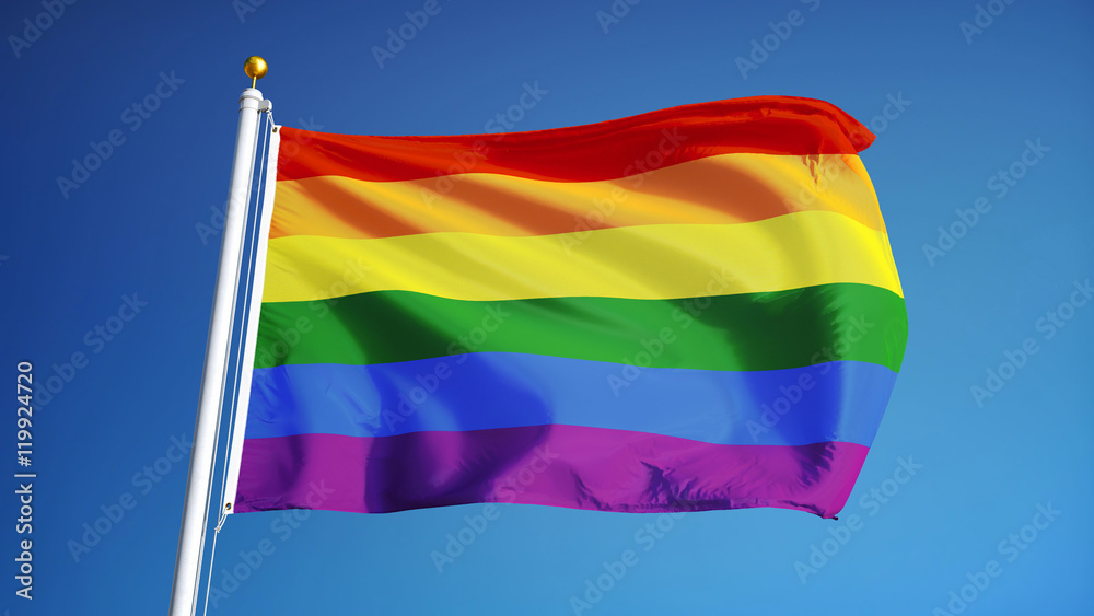 The gay pride rainbow flag waving against clean blue sky, close up ...
