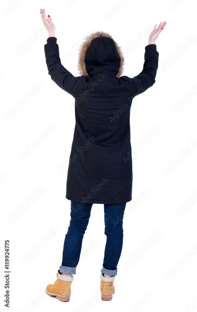 Back view of Beautiful woman in parka looking at wall and Holds hand up ...