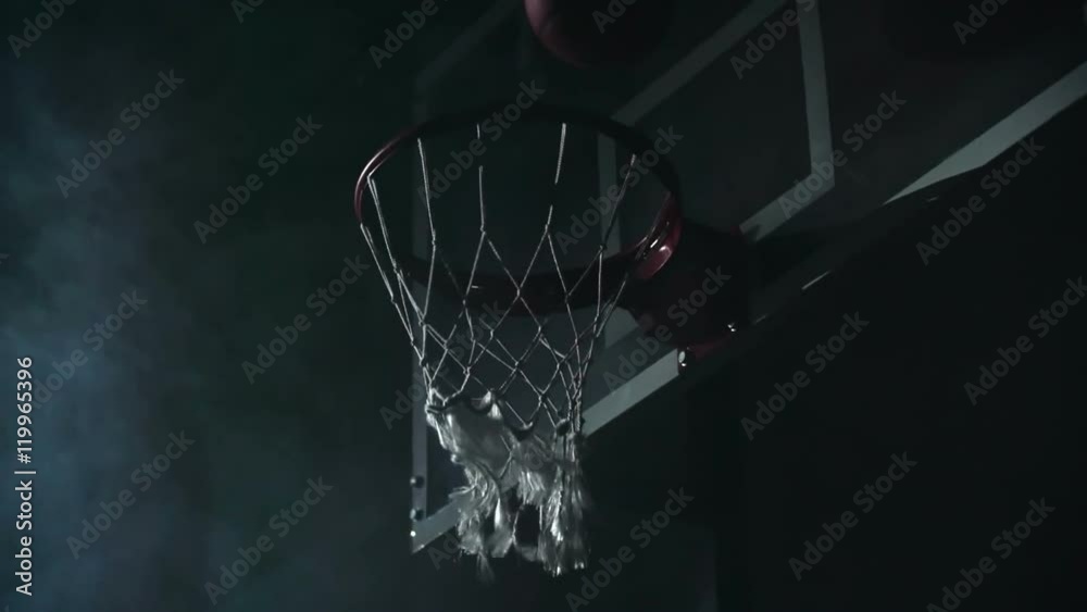 Slow motion shot of ball balancing on rim before falling through the ...