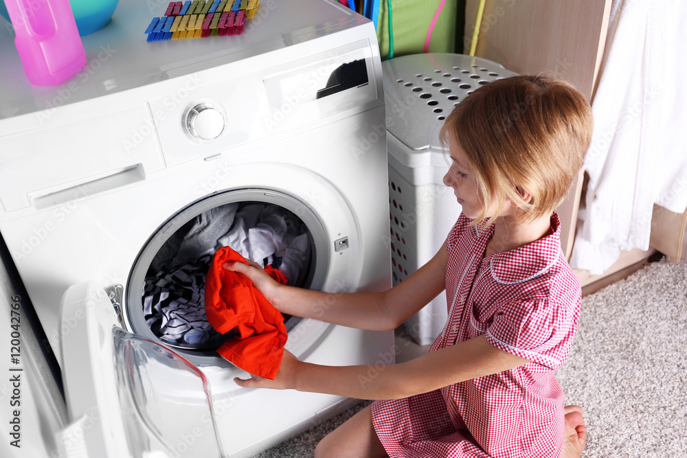 Little girl washing clothes in the machine Stock Photo | Adobe Stock