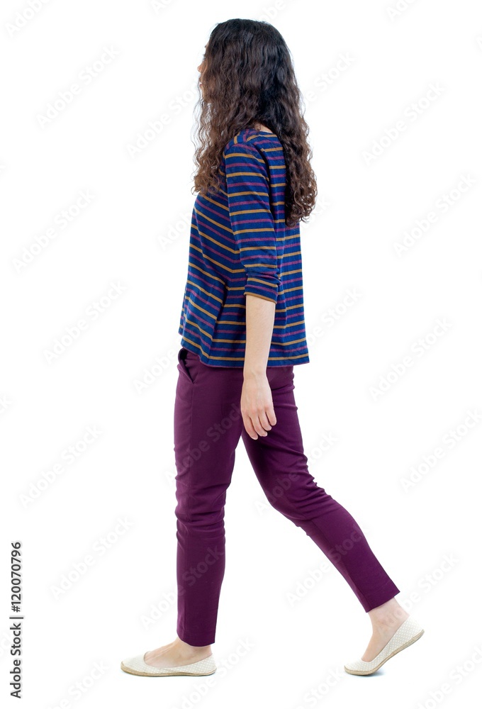 back view of walking curly woman. Long-haired curly girl goes past the ...