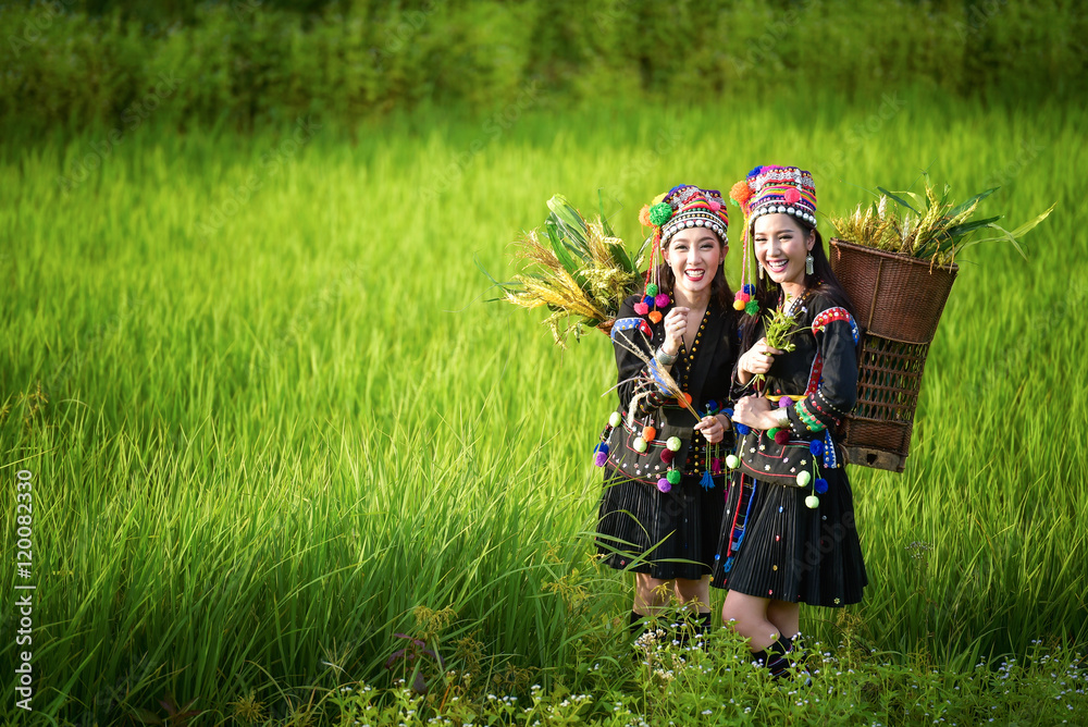 Two women wearing tribal costumes work in the fields of rice terraces ...