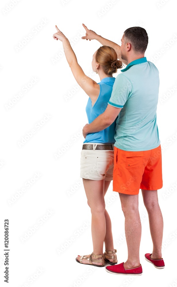 young couple in shorts and t-shirt pointing. Back view. Rear view ...