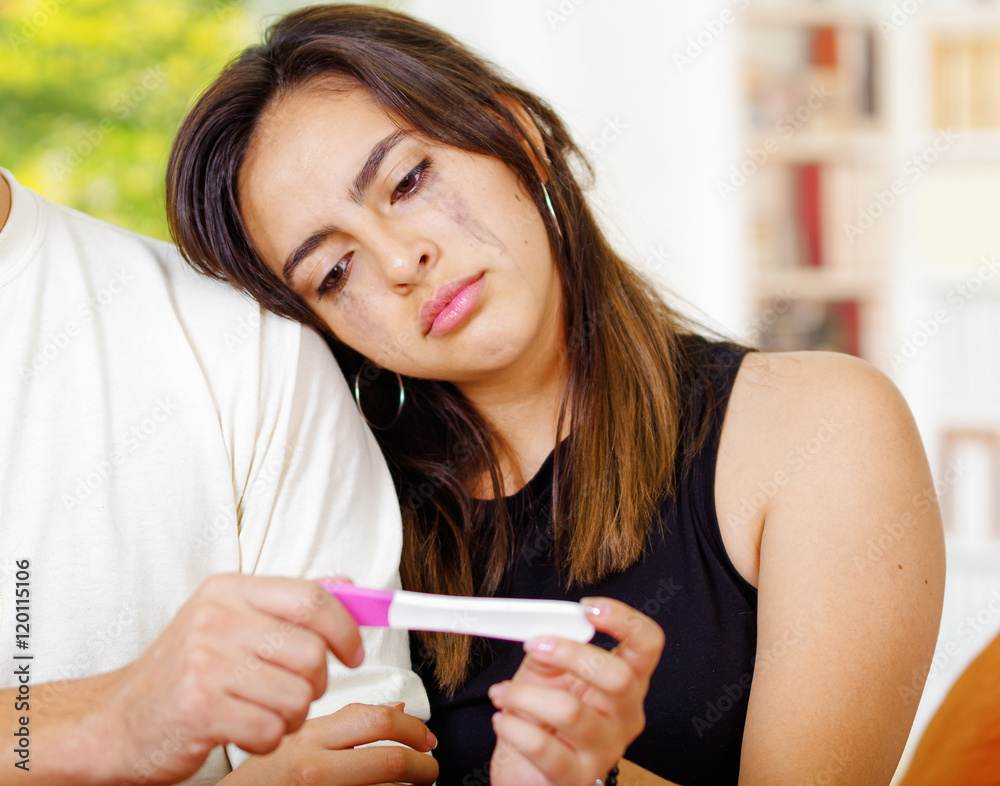 Pretty young brunette woman holding pregnancy home test, crying and ...