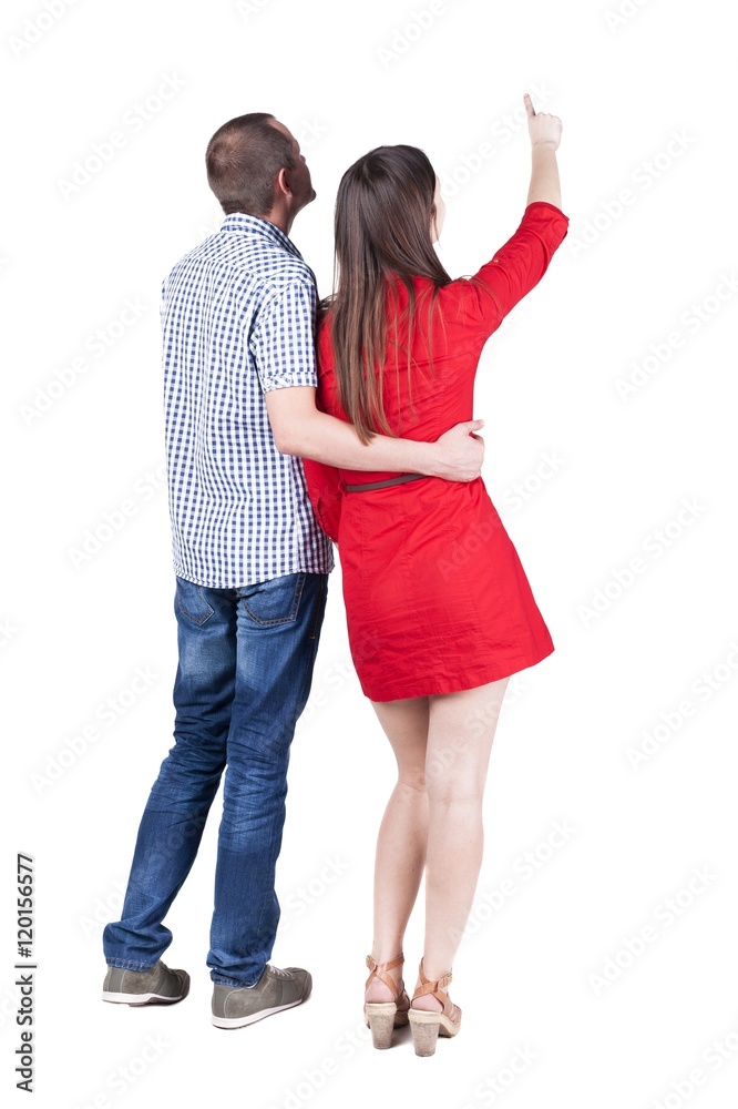 young couple pointing at wal Back view woman and man . Rear view people ...