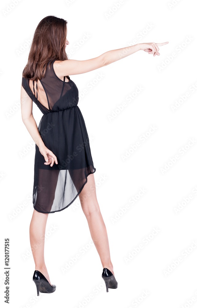 Back view of young brunette woman pointing at wall. beautiful girl in ...