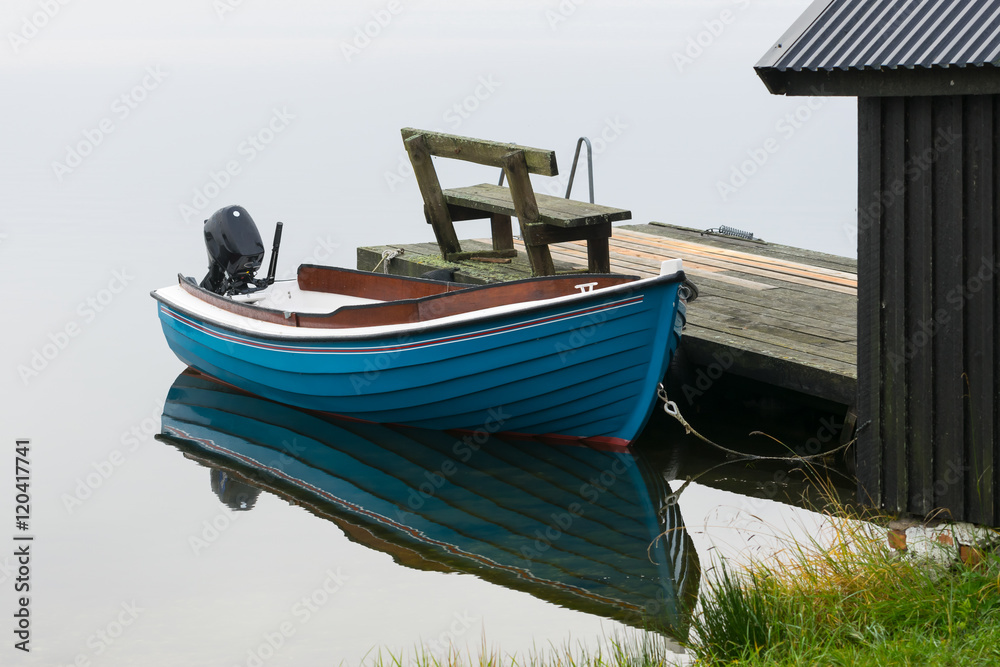 Kleines blaues Fischerboot im spiegelglatten Wasser im kleinen ...