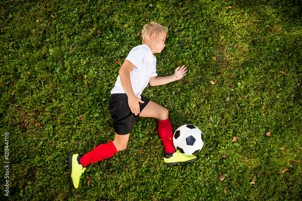 Aspiring young kid is seen training soccer / football on a local ...