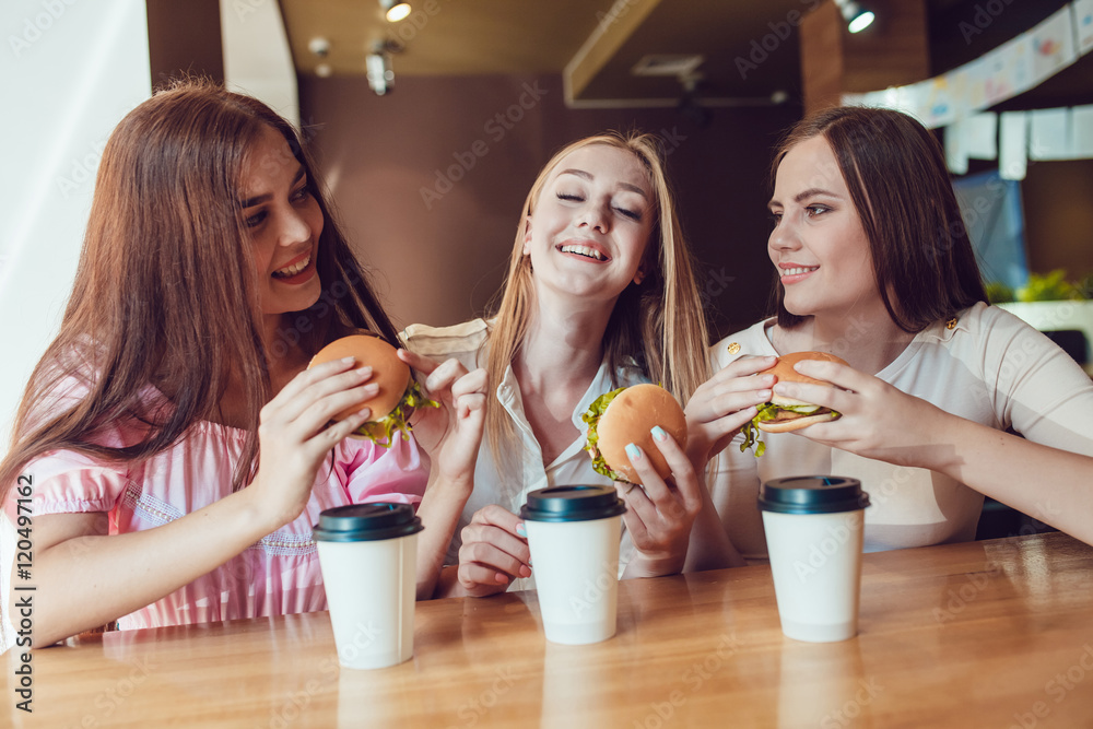 Three cheerful young girls eating fast food in a restaurant Stock-Foto ...