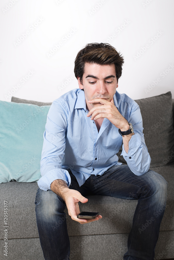 Sad man looking at his phone while sitting on sofa Stock Photo | Adobe ...
