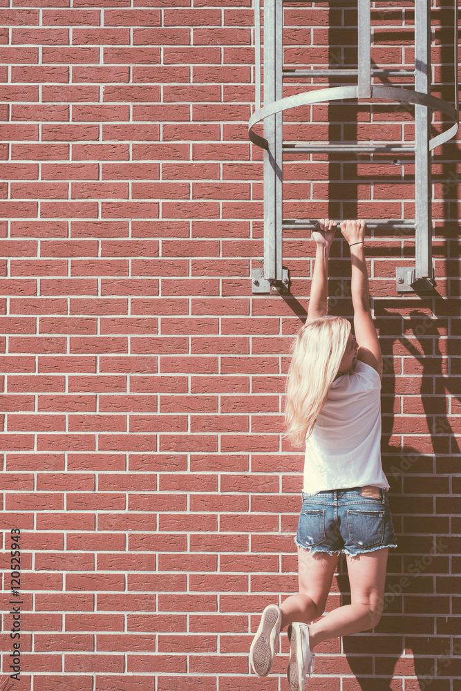Blonde woman hanging on fire ladder Stock Photo | Adobe Stock