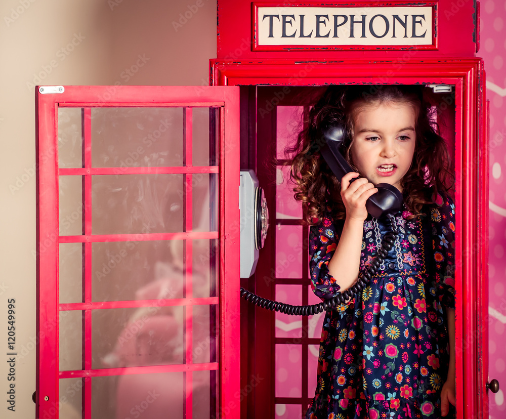 little girl hides and plays in a traditional red telephone booth Stock ...