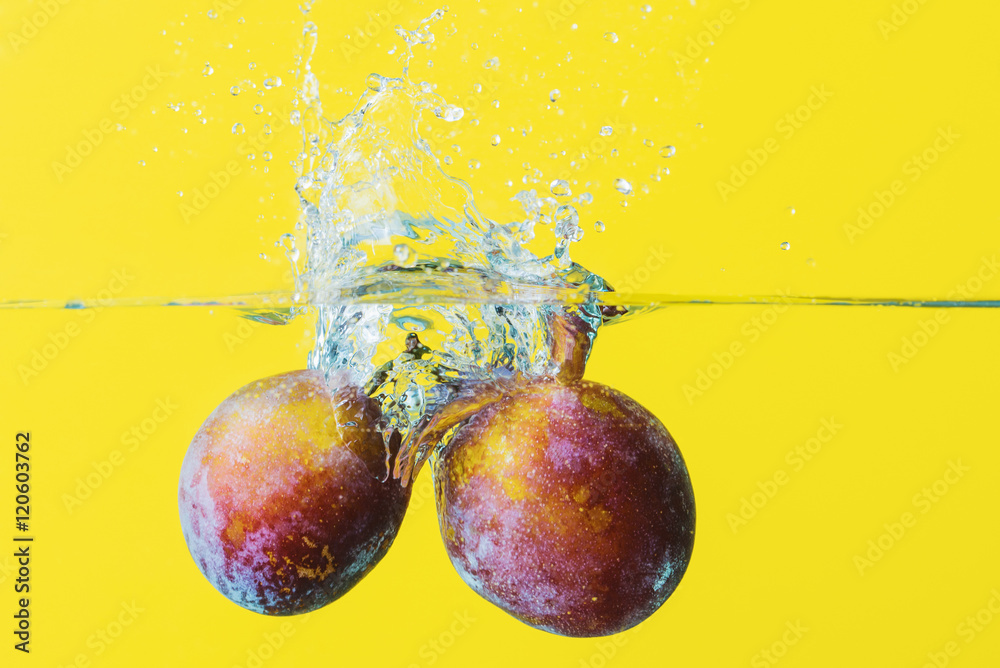 Plum in water with splash over yellow background Stock Photo | Adobe Stock