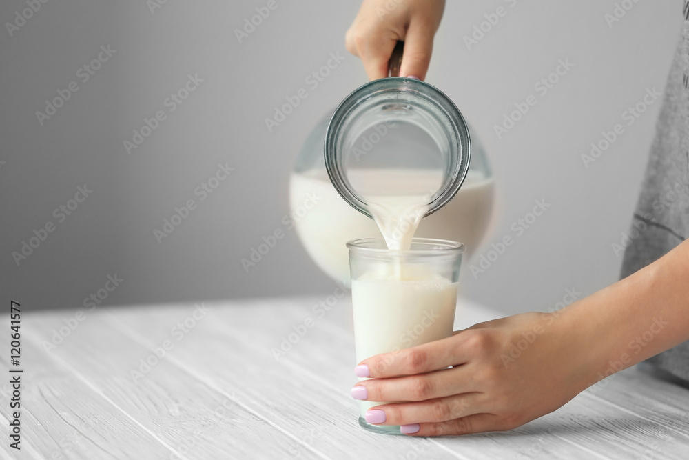 Female hand pouring milk from a jug into a glass Stock Photo | Adobe Stock