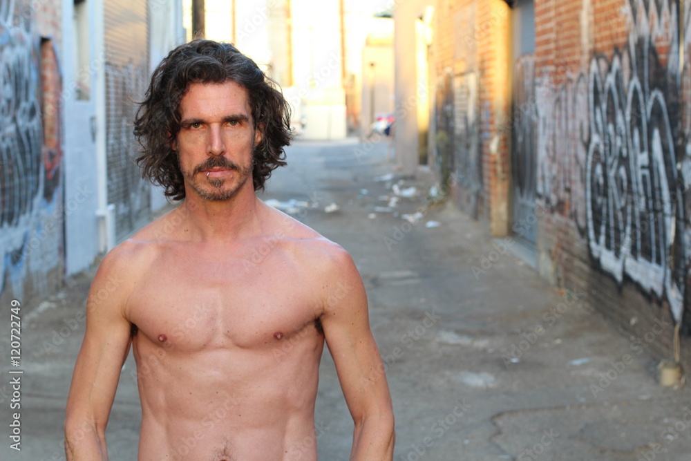 Handsome man with long hair and beard. He is posing in front of camera ...