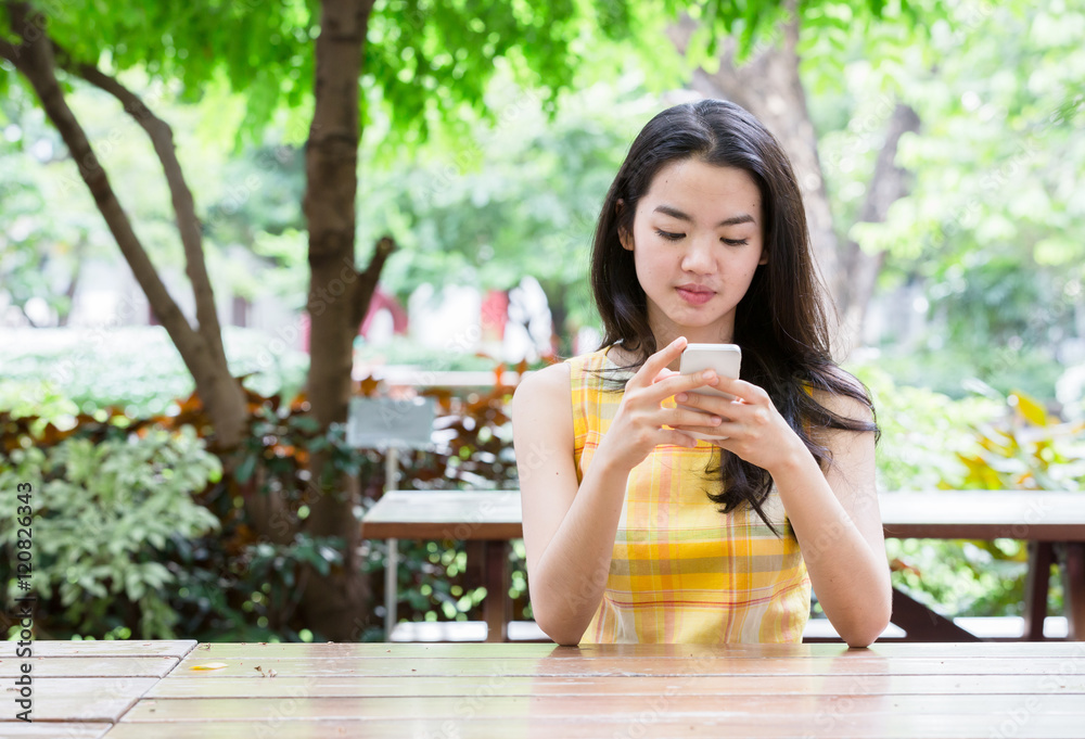 Young asian woman happily using a smart phone Stock Photo | Adobe Stock
