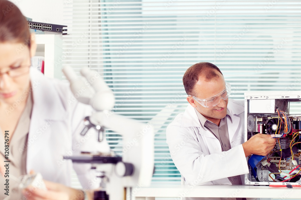 Focus on male technician sitting at the table and examining computer ...