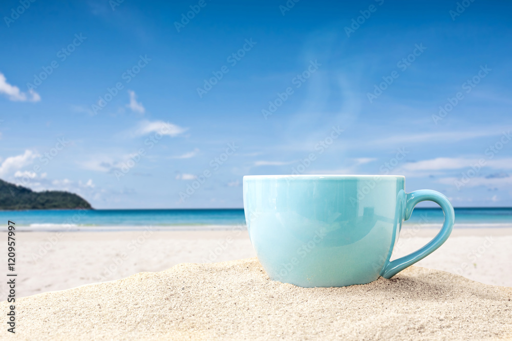 blue cup of coffee on white sand beach over blue sky and sea on day ...