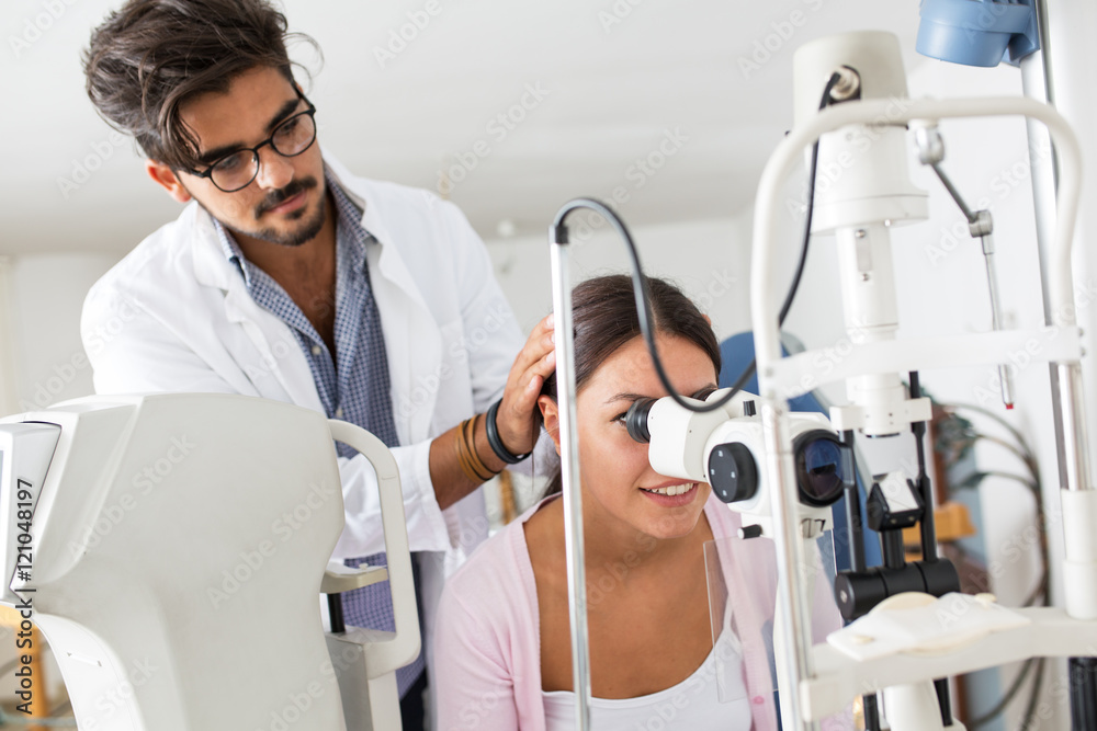 Optometrist with eye tonometer checking patient intraocular pressure at ...
