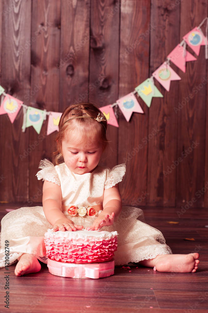 Kid girl eating birthday cake sitting on wooden floor in room. Wearing ...