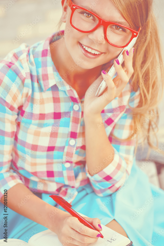 Girl speaks by phone and taking notes. Stock Photo | Adobe Stock