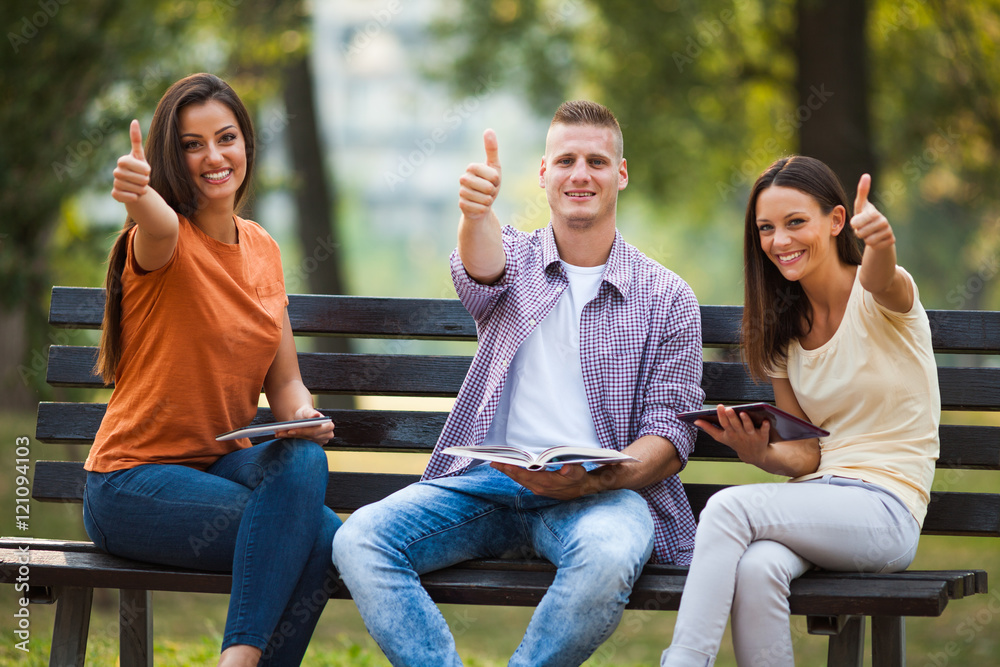 Three students are sitting on bench in park and learning. foto de Stock ...