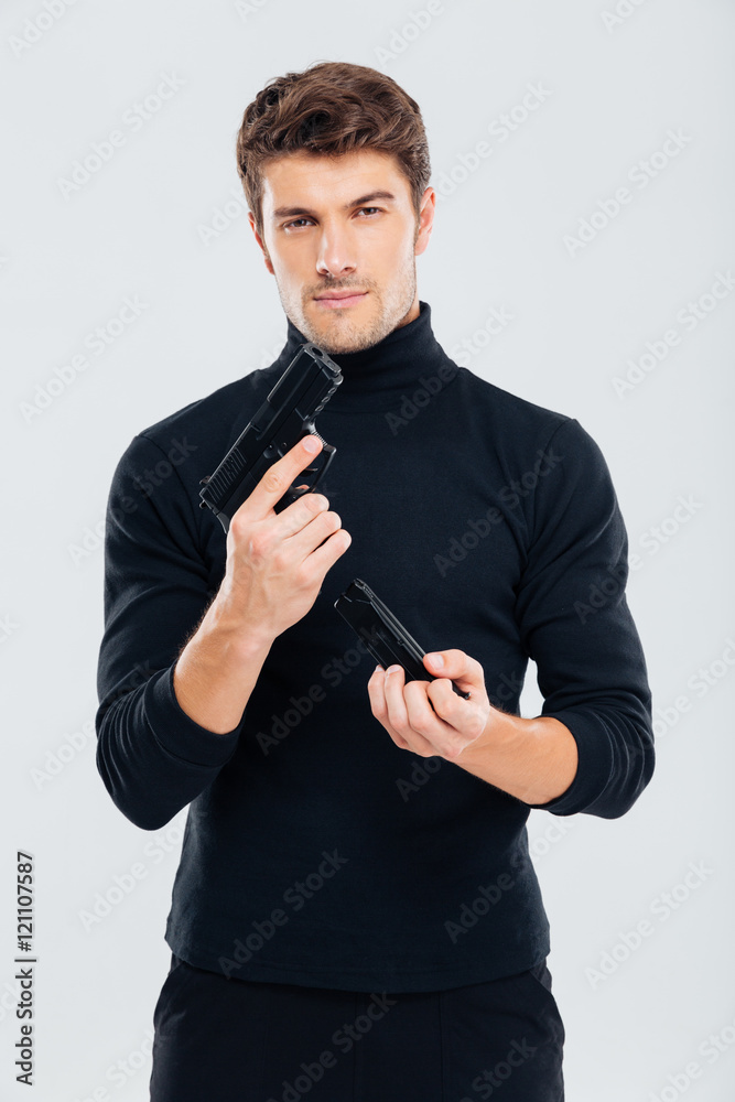 Serious young man standing and loading a gun Stock Photo | Adobe Stock