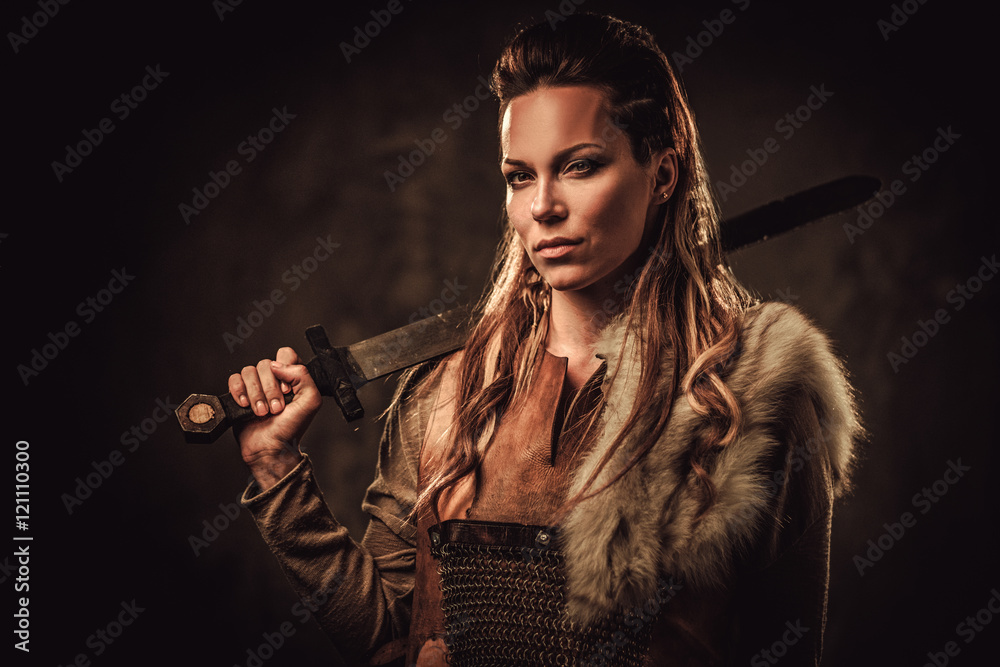 Viking woman with sword in a traditional warrior clothes, posing on a ...