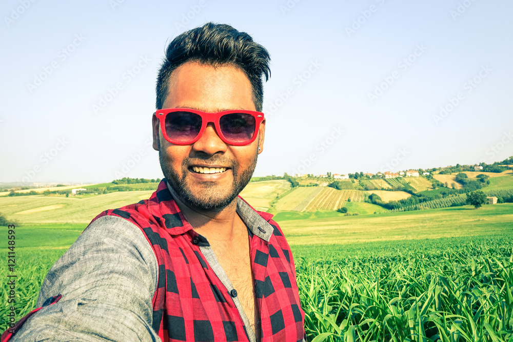 Young indian man taking selfie at green corn field with country hills ...