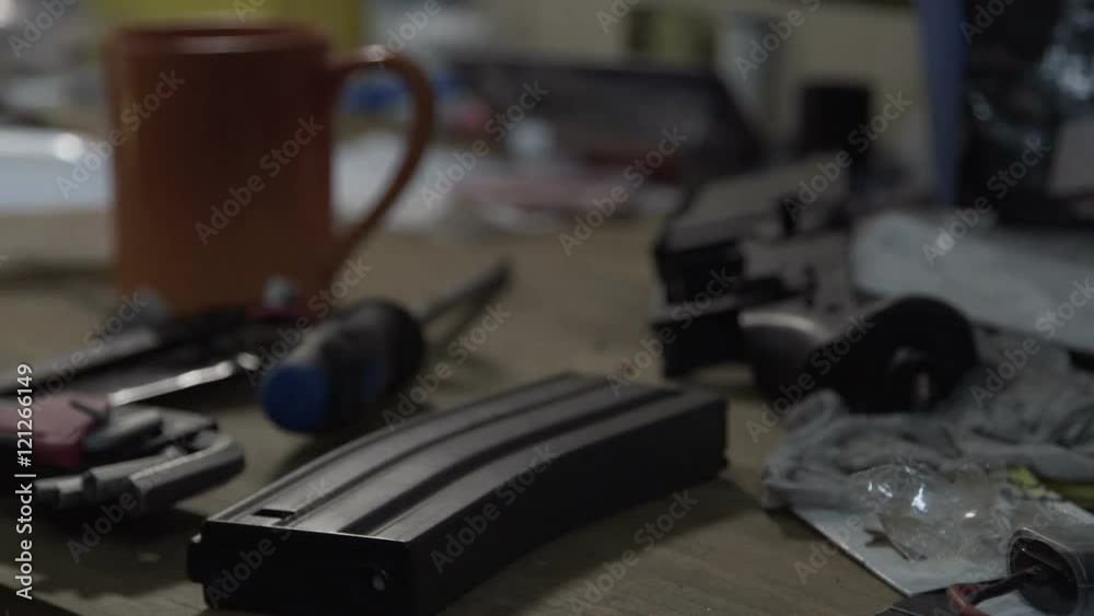 Man repairing a machine gun. Table with tools for repair of weapons ...
