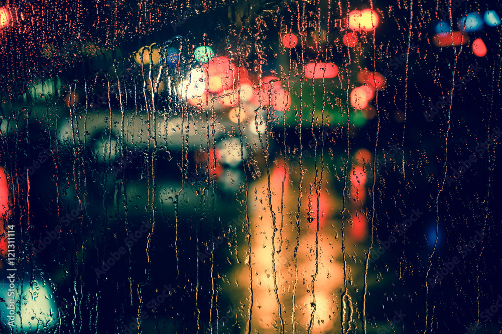 City view through a window on a rainy night,Rain drops on window with ...