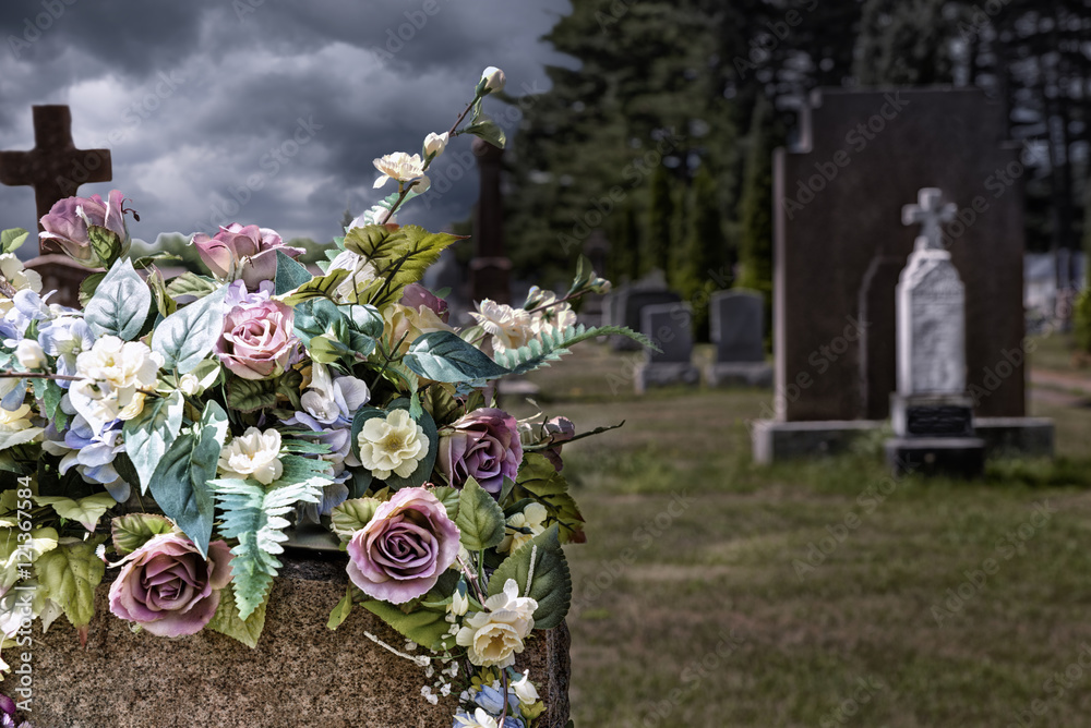 Flowers on a headstones in a cemetery, bokeh effect in background ...