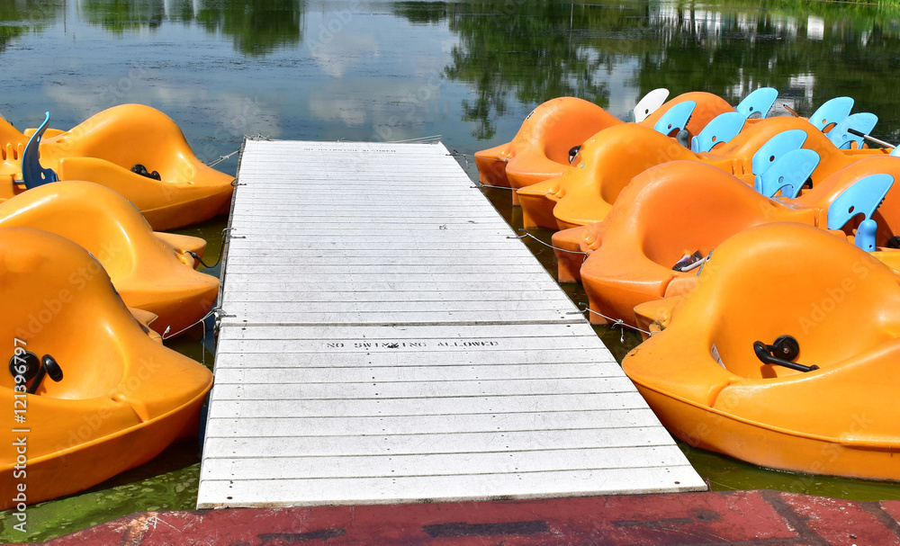 Paddle boats along a dock in a pond Stock Photo | Adobe Stock