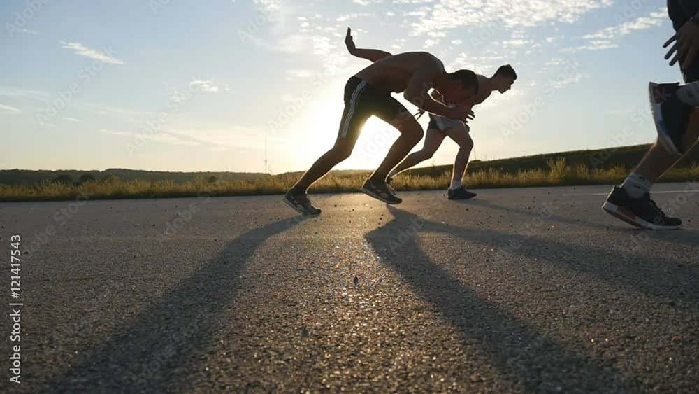 Group of athletes are crouching at starting line before a race and ...