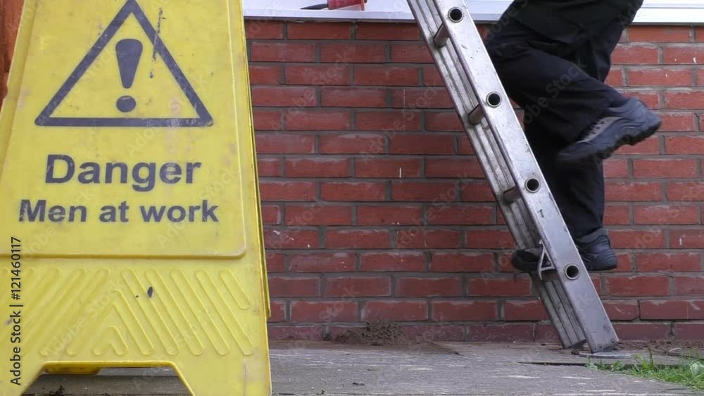 Man wearing high vis vest, safety shoes and carrying trowel and hammer ...
