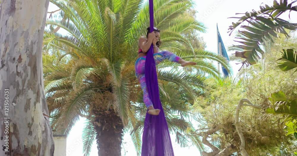 Supple gymnast giving an acrobatic dance performance hanging upside ...