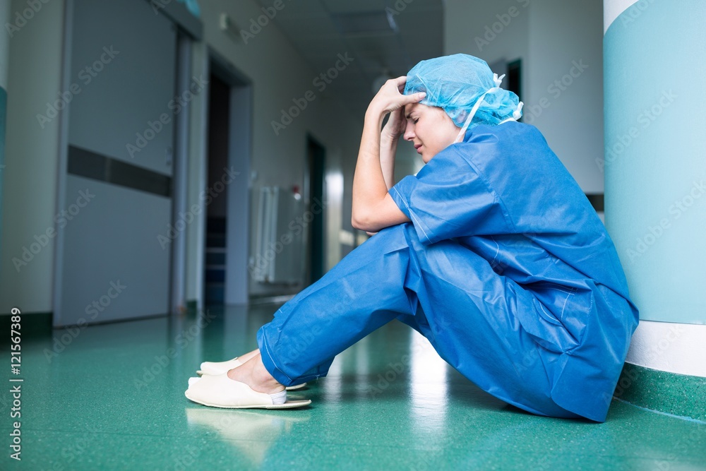 Foto de Sad surgeon sitting on floor in corridor do Stock | Adobe Stock