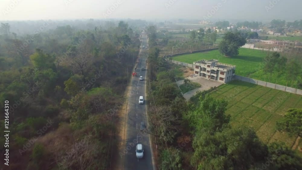 Aerial shot over a two lane road in rural India. Many cars, motorcycles ...