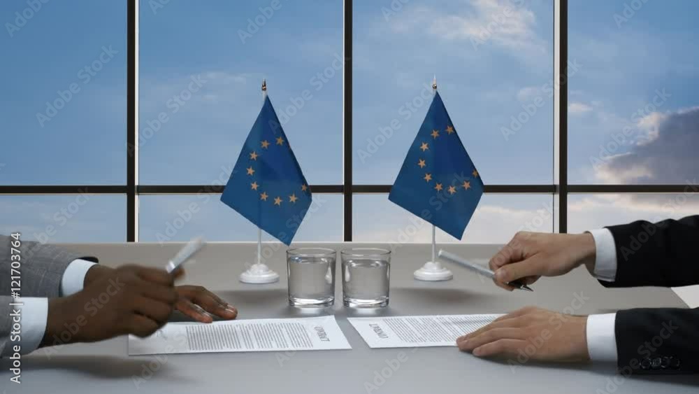 Hands of men sign papers. Businessmen shaking hands near flags ...