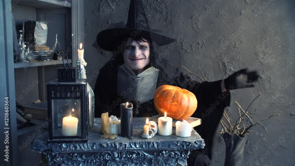 Halloween witch sitting at a table and waving his hand Stock Video ...