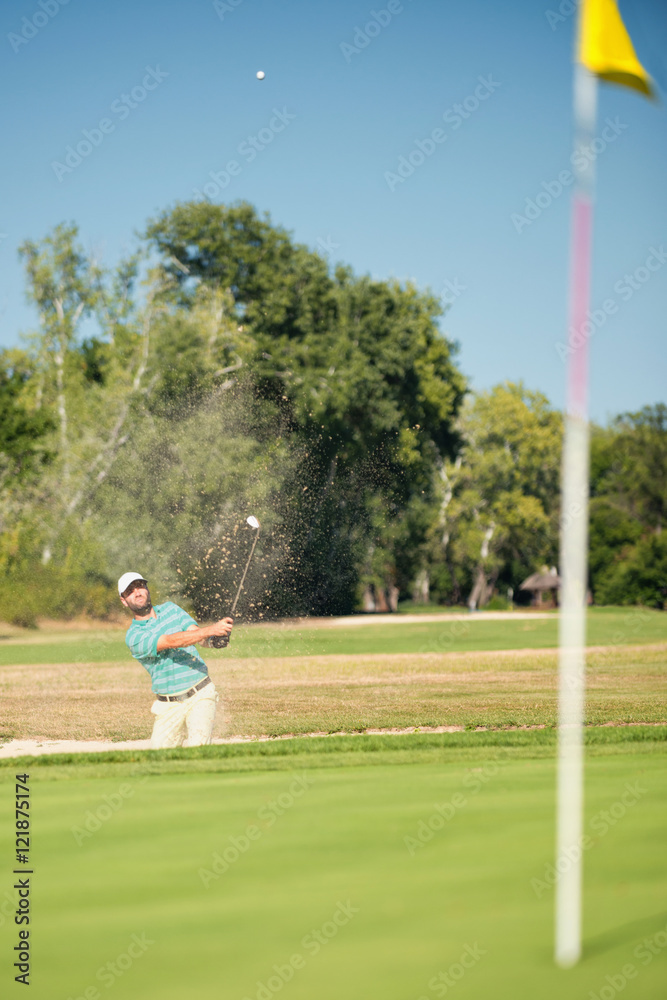 Golf. Perfect flop shot out of sand. Ball high in the air, sand flying ...