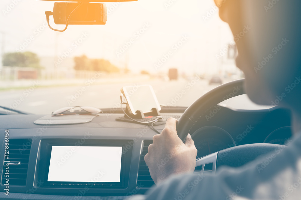 Young man driving car on road with blank screen monitor using connected ...