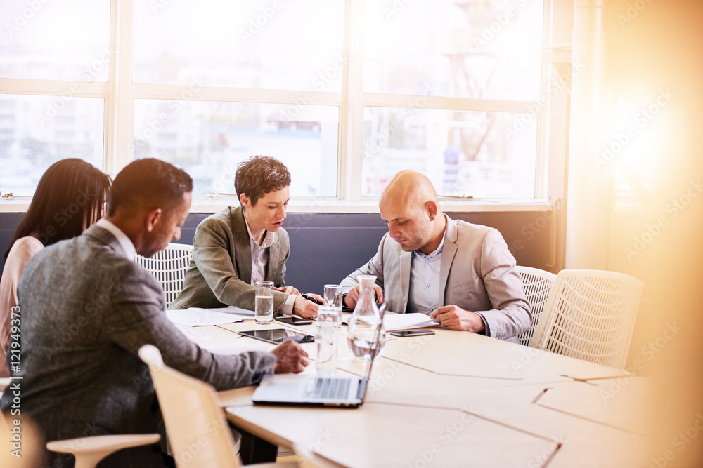 Four business professionals conducting a meeting in a bright modern ...