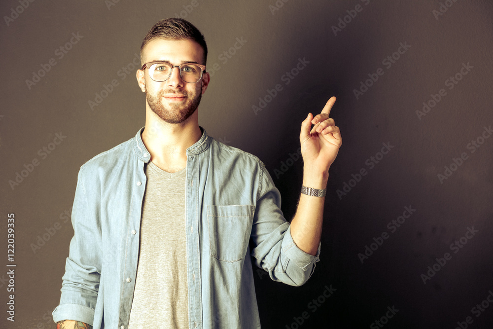 Foto de Portrait of a smiling young man pointing up do Stock | Adobe Stock