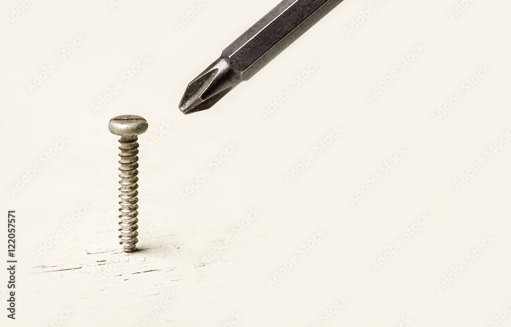 screwdriver and screw on old white wood with copy space, wrong tool for ...