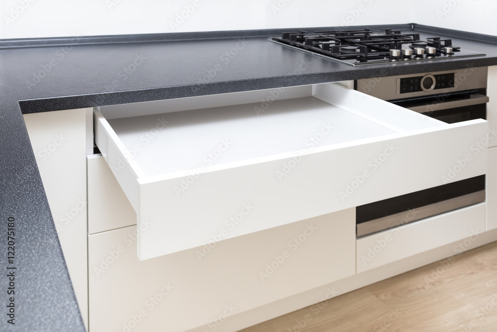 Opened white drawer in a kitchen cabinet with an handleless front, tip ...